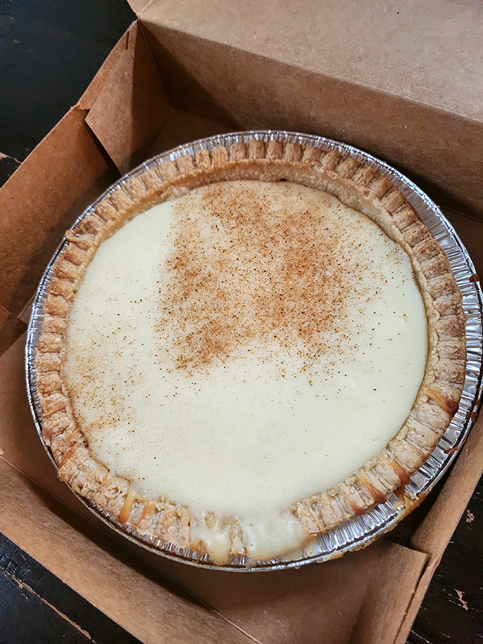 A chocolate cream pie peeks from its box like a shy celebrity, knowing its autograph (in the form of empty plates) will be sought after dinner.