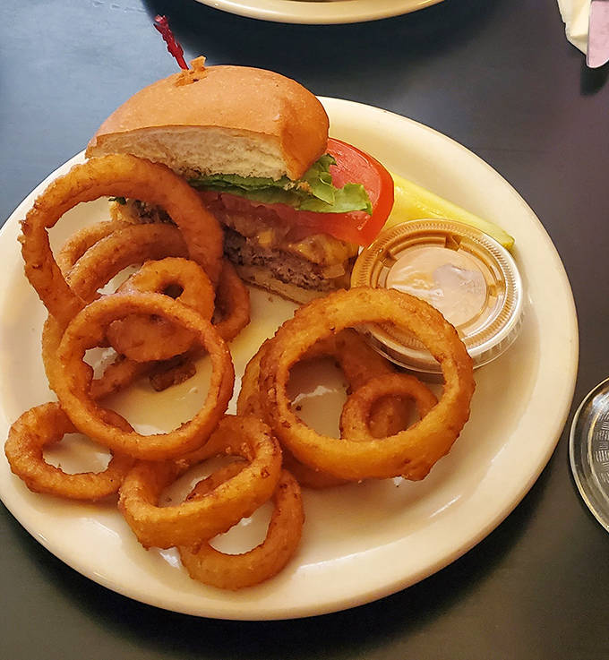 Crispy onion rings form a golden halo around a perfectly stacked burger &ndash; a combination that makes you grateful for simple pleasures.