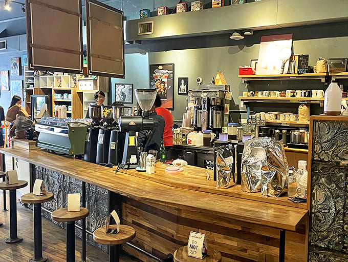Behind this wooden counter, baristas craft exceptional beverages with scientific precision while surrounded by pop culture artifacts from another era.