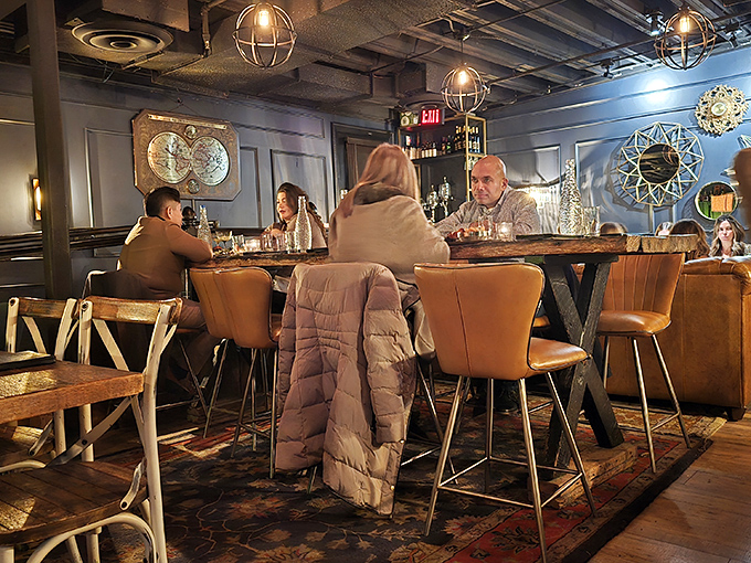 The communal table invites strangers to become friends – shared stories flow as freely as the expertly crafted cocktails.