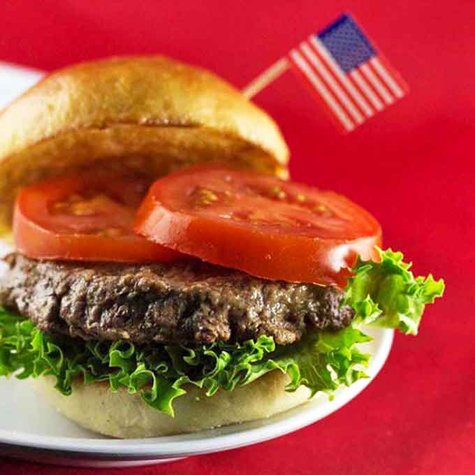 This isn't just a hamburger – it's an American dream on a bun, complete with a tiny flag that seems to say "Mission Accomplished" to your hunger.