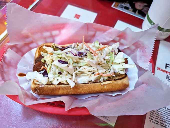 A fresh, crisp coleslaw crowns this hot dog like a tiara, adding crunch and tang to balance the savory sausage beneath.