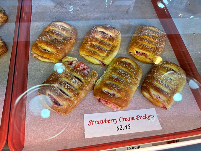 Strawberry cream pockets glisten in their display case, the perfect handheld treat for berry lovers seeking pastry perfection.