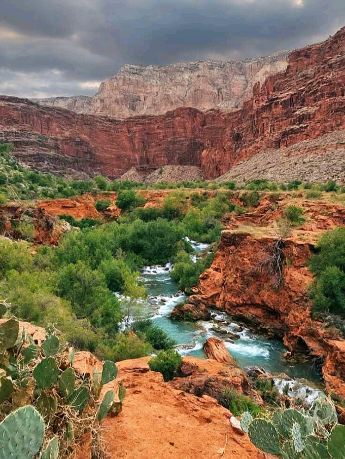 Desert meets oasis: Ancient rock formations frame the vibrant blue creek, showcasing Arizona's geological diversity in one stunning view.