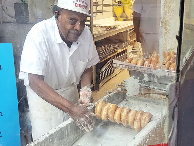 Skilled hands at work&mdash;decades of donut-making expertise transform simple ingredients into neighborhood-famous treats with practiced precision.
