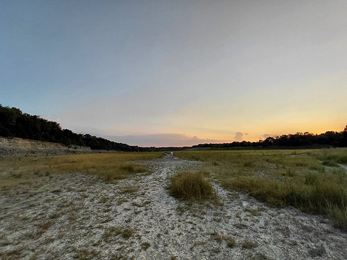 The trail stretches into the distance across open meadows, where the horizon promises adventure just beyond the next step.