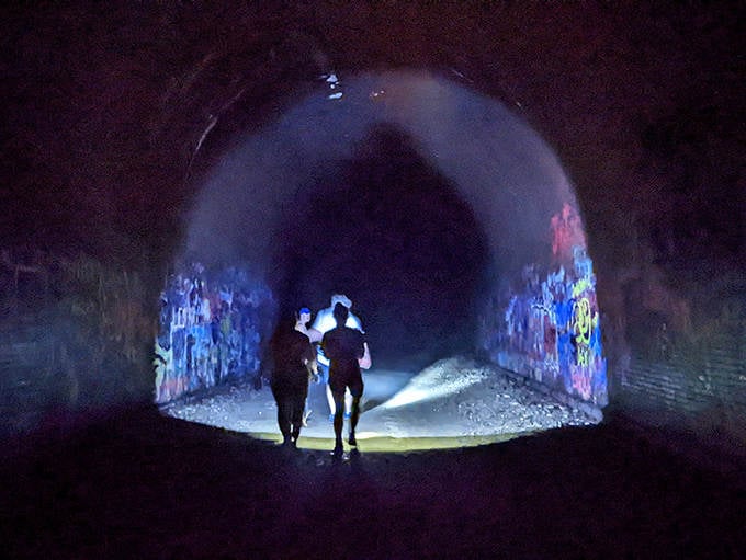 Brave souls venture into the darkness, their flashlights creating eerie shadows that dance along ancient bricks.