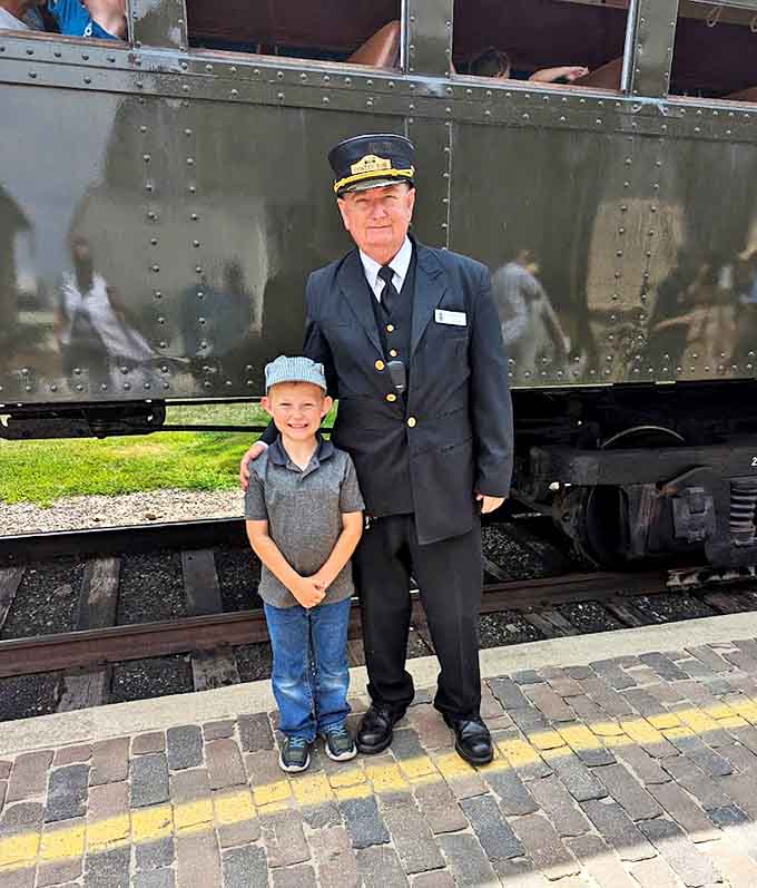 Creating memories that will last a lifetime – a young train enthusiast poses with a conductor whose uniform and demeanor perfectly capture railroading's golden age.