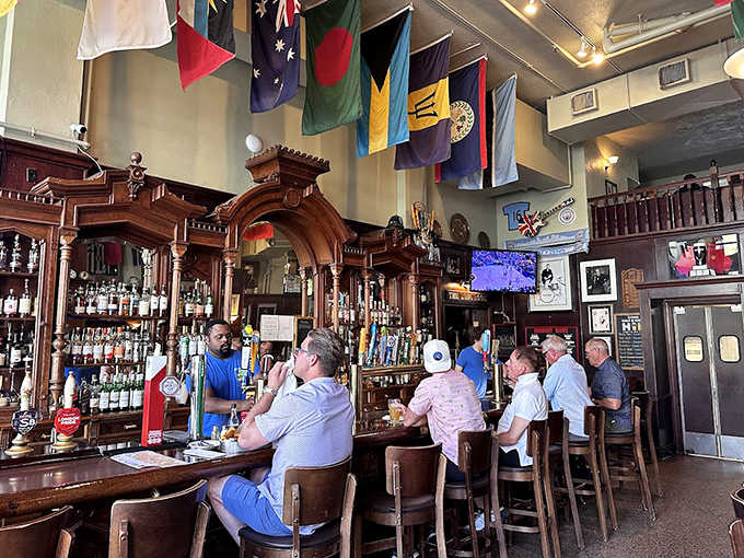 The magnificent bar area showcases an impressive selection of spirits beneath international flags, creating a worldly atmosphere for enjoying a proper pint.