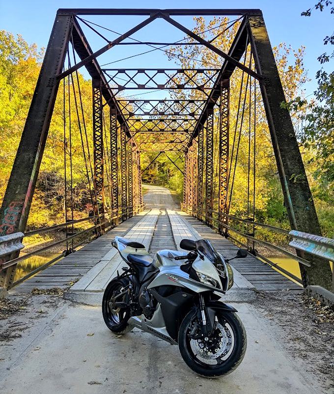 A motorcycle waits at the bridge entrance, its rider perhaps gathering courage before crossing this legendary structure.