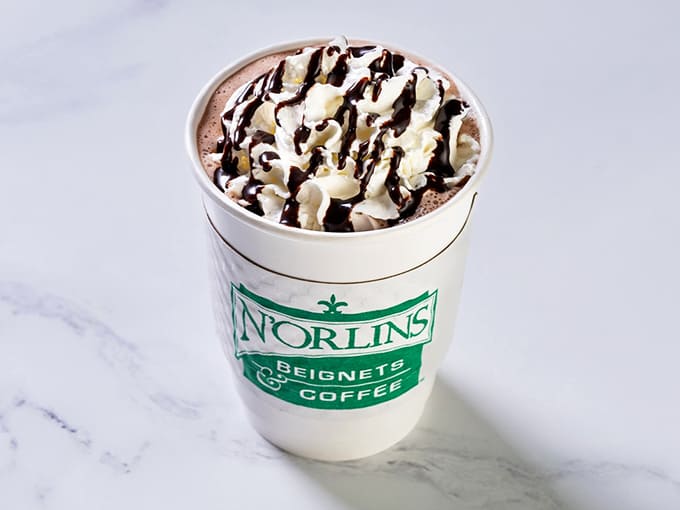 Hot coffee topped with frothed milk and a drizzle of chocolate, because sometimes you need your caffeine to feel like a hug.