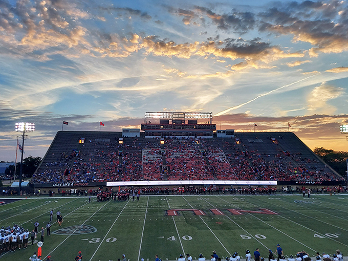 Huskie Stadium glows with electric energy as sunset paints the sky, transforming an ordinary evening into a cathedral of collegiate pride and athletic drama.