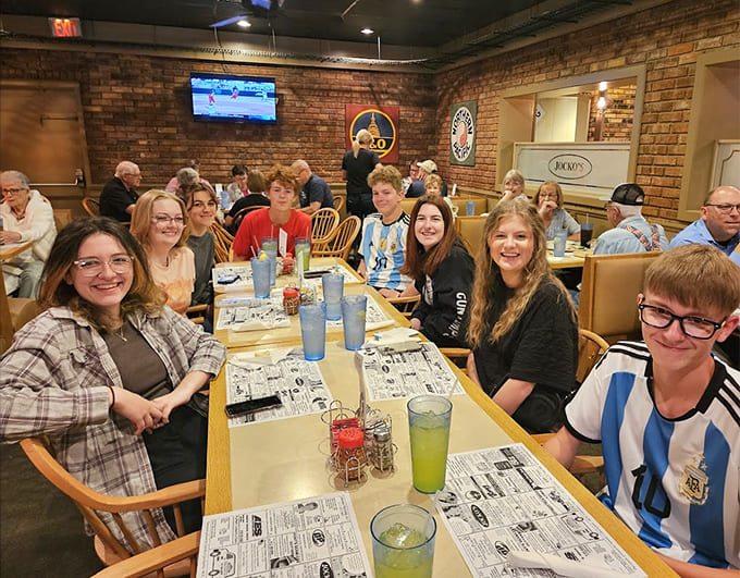 Happy diners gathered around tables full of food, this is what community and good eating look like together.
