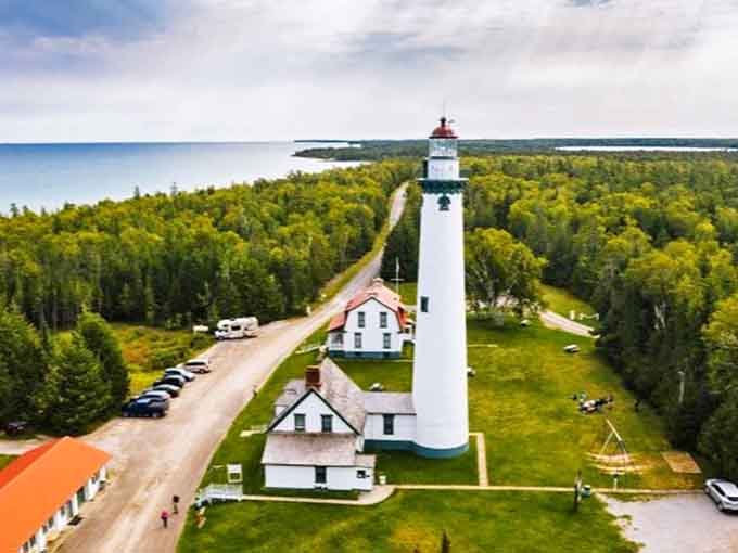 From above, the lighthouse complex reveals its perfect positioning, standing guard where forest meets water in a quintessentially Michigan landscape.