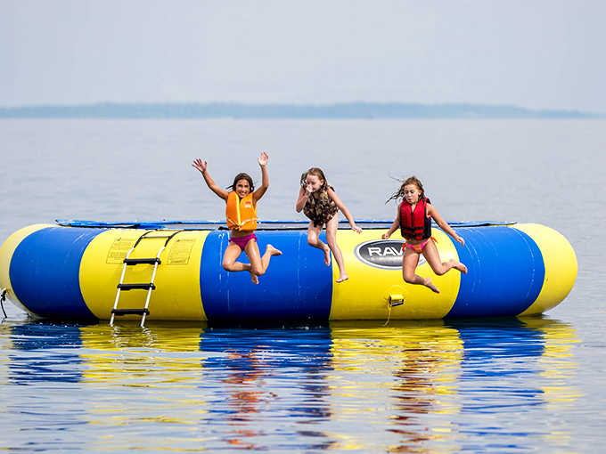 Pure Minnesota joy captured mid-air – three young adventurers discovering the perfect combination of bounce, splash, and summer freedom.