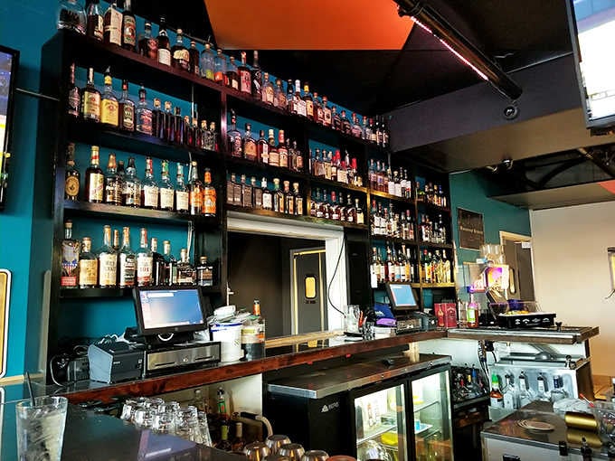 The whiskey collection glows like amber treasure against the teal wall &ndash; a library of spirits that would make a prohibition agent weep.