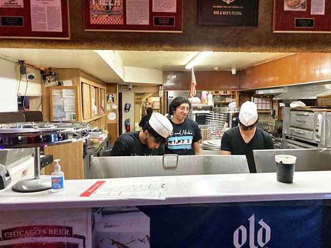 Behind the counter, skilled hands continue traditions passed down through generations, crafting each pizza with practiced precision.