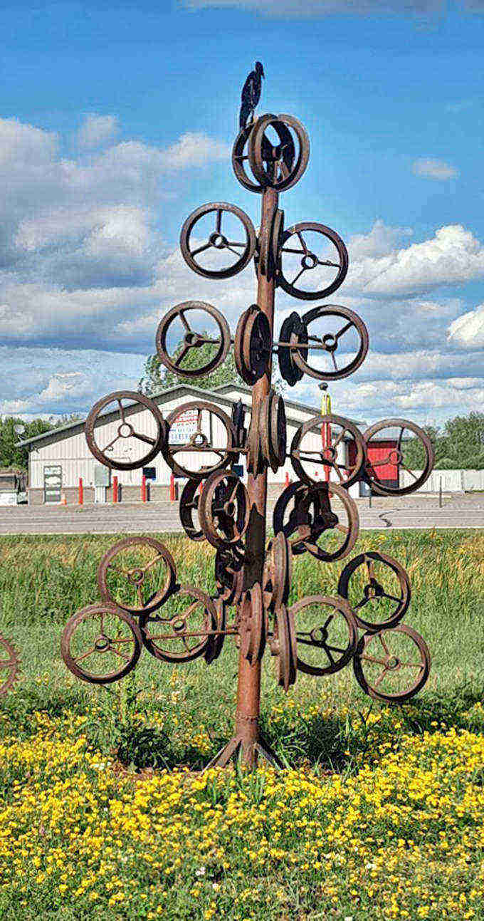 The wheel tree blooms year-round with steering wheels instead of leaves, a mechanical forest growing stubbornly in the heart of farm country.