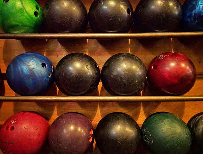 Colorful bowling balls await their turn to shine, each promising the possibility of that elusive perfect game.