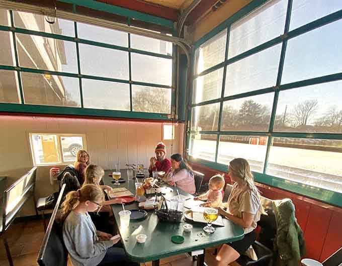 Families gather in the sunlit dining area, sharing slices and creating memories in a space where train passengers once waited for their journeys.