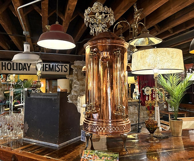 A magnificent copper column steals the spotlight among vintage lamps and glassware, gleaming like a beacon of bygone elegance.
