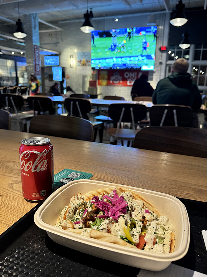 A Mediterranean wrap from Zaki Grill sits ready for enjoyment, its colorful fillings and creamy sauce promising a flavor explosion with every bite.