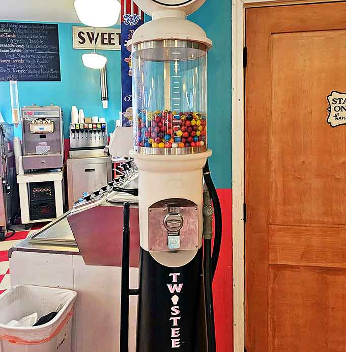 The gumball machine stands as a colorful sentinel of simpler pleasures, where a quarter still buys a moment of childhood joy regardless of your age.