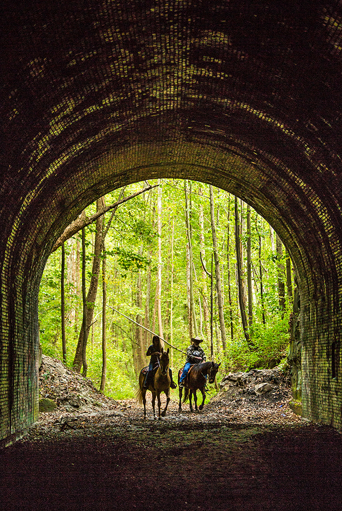 Light at the end of the tunnel creates a perfect silhouette for horseback riders emerging from the darkness.