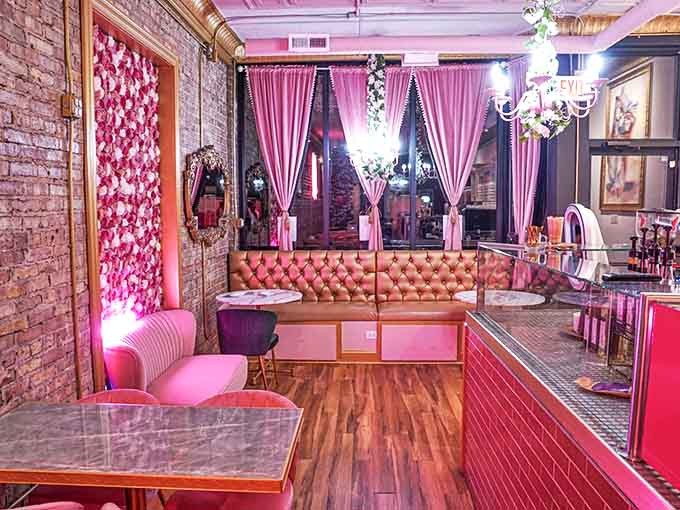 Pink curtains filter sunlight into a rosy glow, creating an atmosphere that feels both indulgent and somehow like coming home.