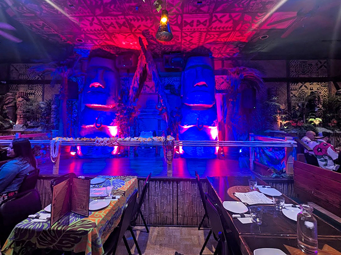 Dramatic lighting transforms the dining space into an otherworldly grotto where blue and red hues dance across stone-like surfaces.