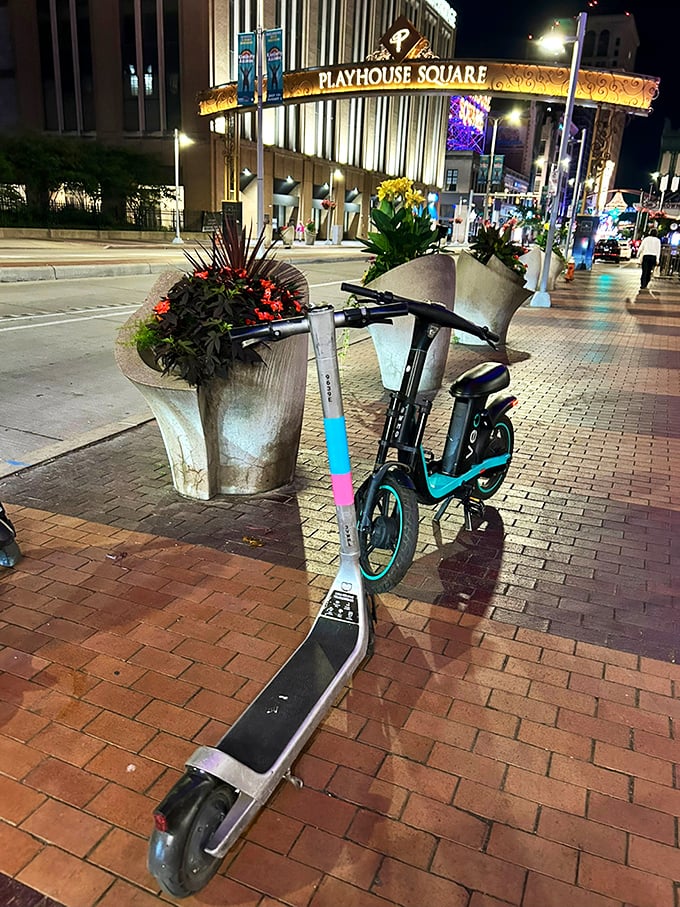 Modern transportation meets vintage glamour as electric scooters wait for riders beneath the district's twinkling centerpiece.