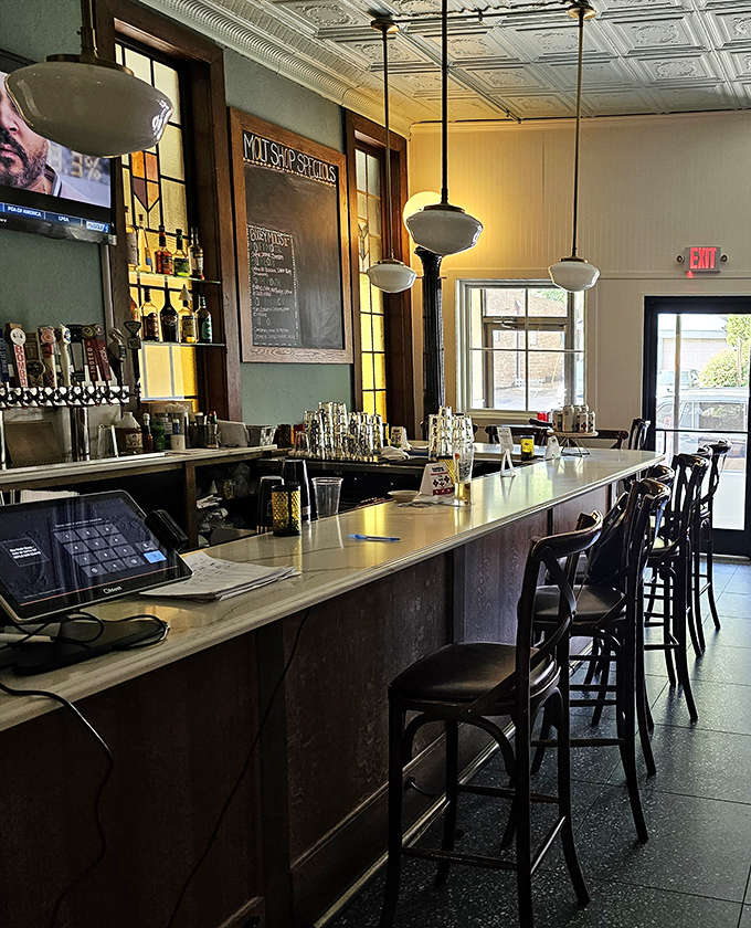 The bar counter gleams under vintage pendant lights, offering the perfect perch for solo diners or those seeking conversation with friendly bartenders.