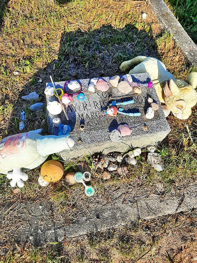 Touching tributes of toys and trinkets surround this child's grave marker, evidence that some spirits still receive visitors after all these years.