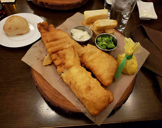 Golden-battered fish and chips arrive with all the proper accompaniments, proving some British exports deserve their legendary status.
