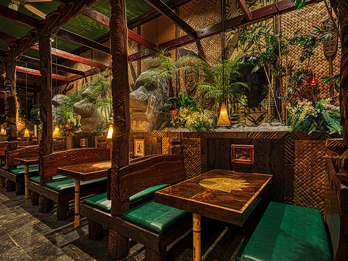 Dining booths carved from dark wood create intimate island hideaways, where bamboo details and thatched accents complete the tropical illusion.