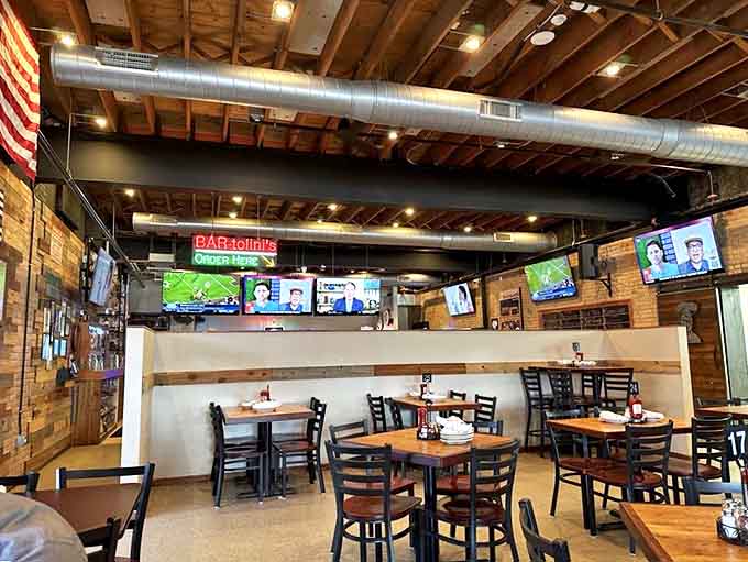 The dining room balances casual comfort with rustic charm, where exposed beams and multiple TVs create the perfect neighborhood gathering spot.