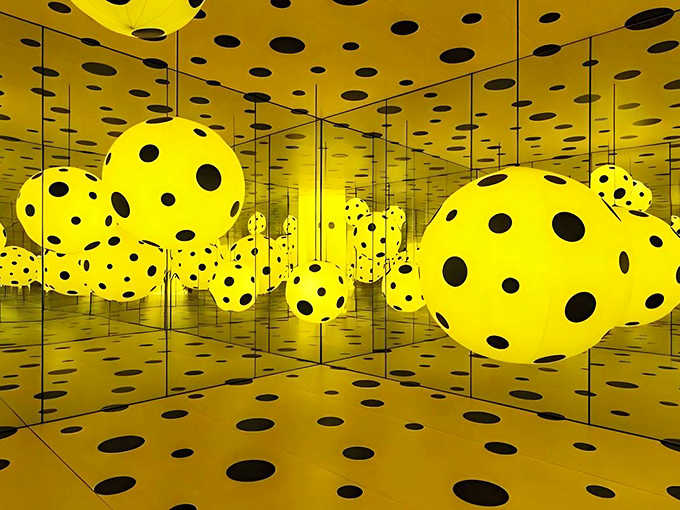 Kusama's yellow "Dots Obsession" room creates a surreal landscape where spotted orbs seem to float in an endless golden universe.