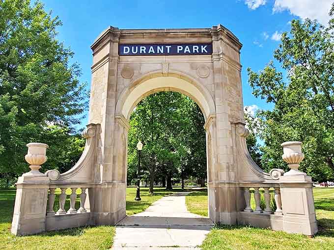 Durant Park's classical stone arch frames a pathway to relaxation, standing as an elegant gateway between urban bustle and natural calm.