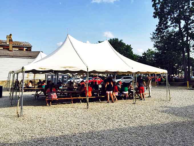 The outdoor tent transforms into a community gathering spot where strangers become friends over shared barbecue bliss.