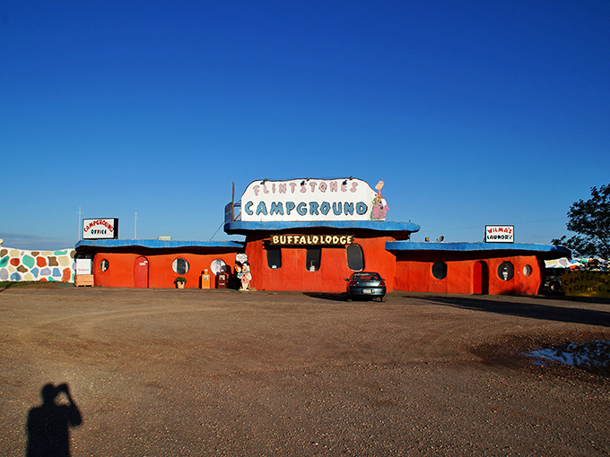 The vibrant orange Flintstone Campground building pops against the desert landscape, a prehistoric oasis for weary travelers.