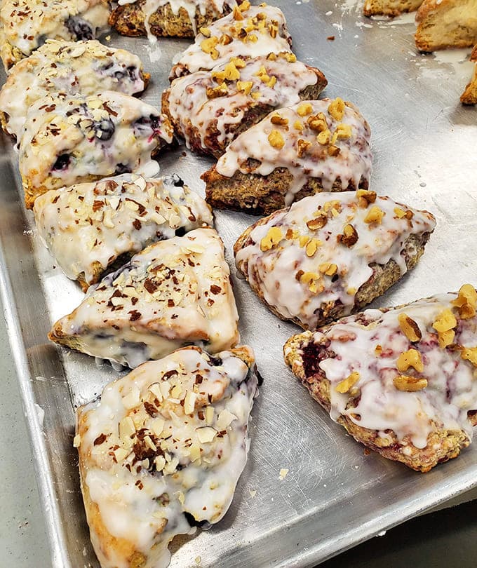 Fresh-baked scones with various toppings and glazes sit ready to elevate your morning coffee routine from mundane to magnificent with every buttery, crumbly bite.