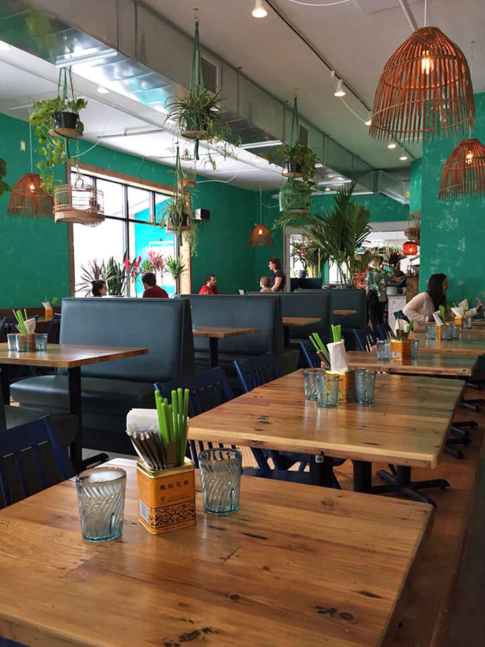 Wooden tables lined against vibrant walls create an intimate dining experience where conversations flow as easily as the cocktails.