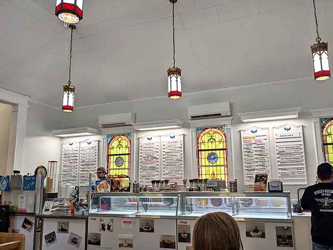 Stained glass windows illuminate the ice cream counter where flavors are displayed like sacred offerings. A different kind of Sunday service happens here.