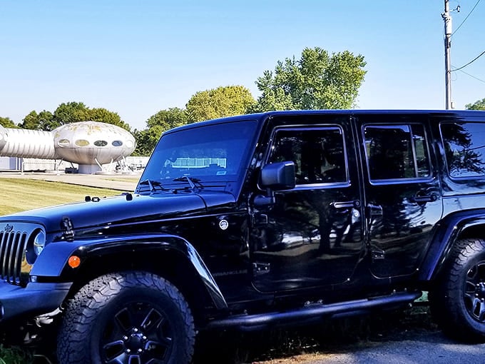 A Jeep parked nearby looks decidedly Earth-bound compared to the futuristic vision hovering just beyond, creating delightful visual contrast.