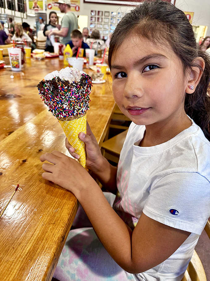 Pure joy radiates from this young ice cream connoisseur, cone decorated with colorful sprinkles. The universal language of ice cream happiness needs no translation.