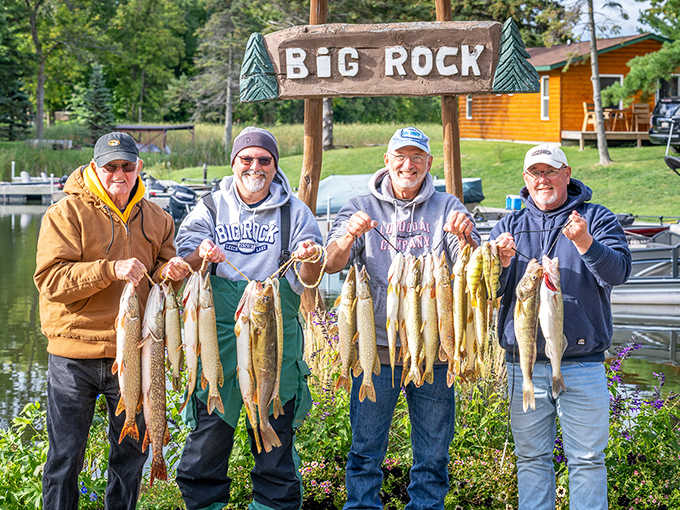 The ultimate Minnesota trophy shot – four proud anglers displaying their impressive catch beneath the Big Rock sign of success.