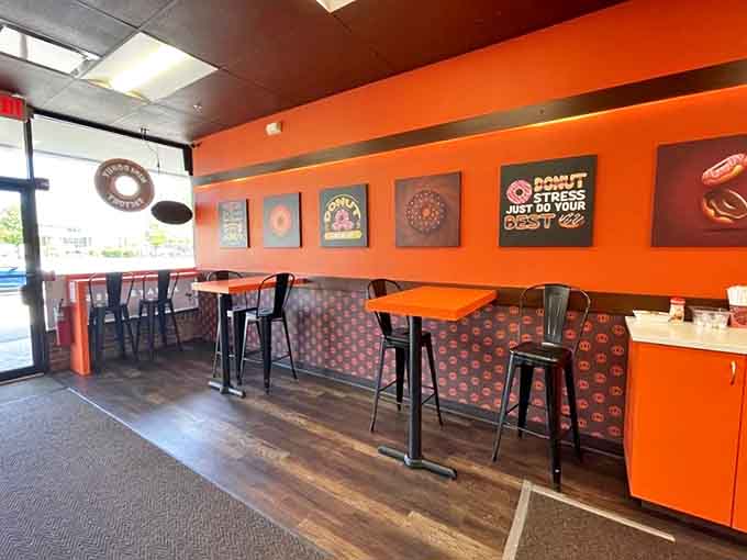 Simple orange tables where donut dreams come true, under the watchful gaze of playful donut-themed wall art.