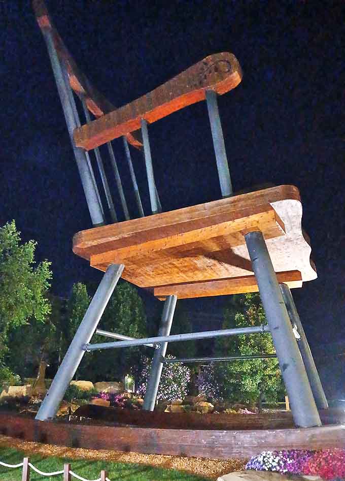 Evening illumination highlights the carved details and creates dramatic shadows that emphasize the chair's impressive architectural elements throughout.