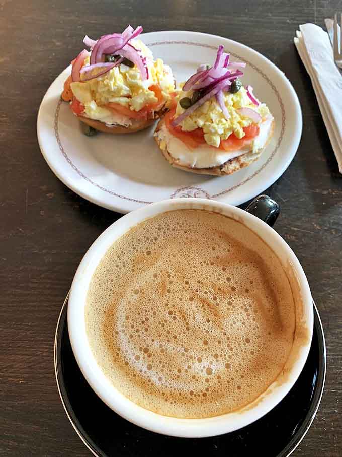 A perfect pairing: velvety oat milk latte alongside a bagel topped with smoked salmon, capers, and red onion &ndash; breakfast elevated to an art form.