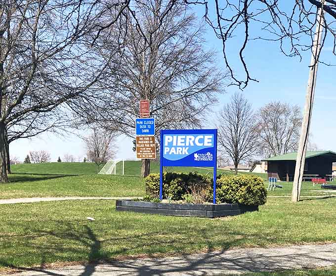 Pierce Park's sign stands amid spring greenery, a humble invitation to enjoy open fields and fresh air without admission fees or complicated rules.